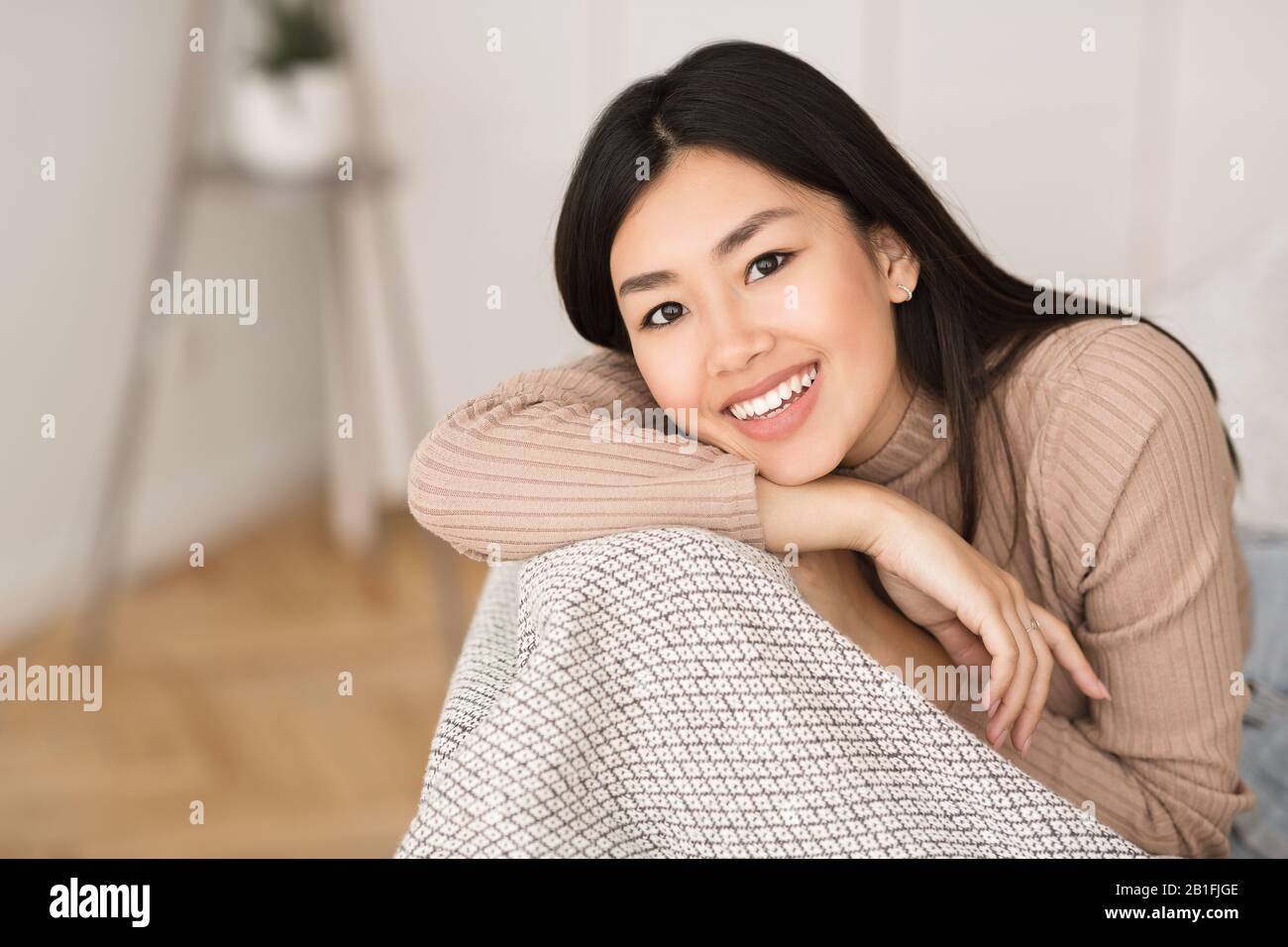 In home comfort. Asian girl smiling to camera Stock Photo - Alamy
