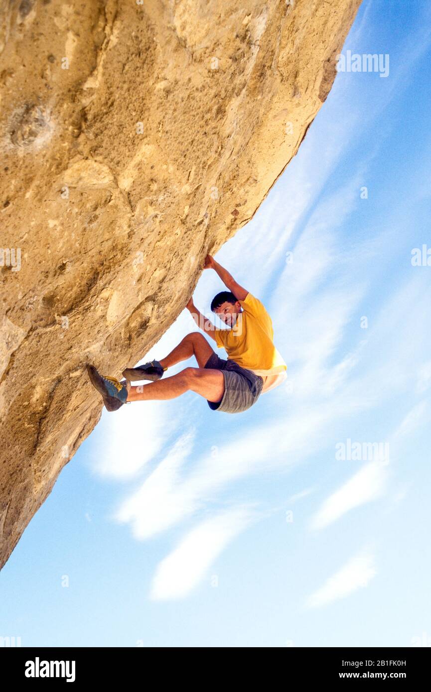 A man climbing up an overhanging rock face Stock Photo - Alamy