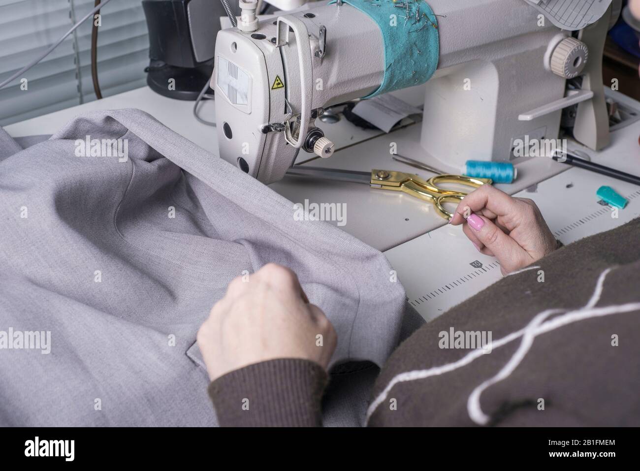 a couturier master, against the background of a sewing machine, sews ...