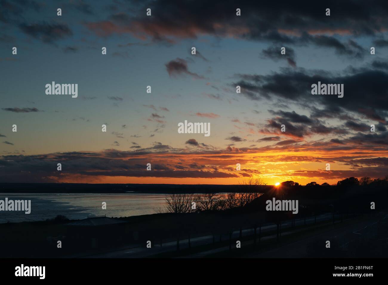 Cloudy sunset over Pegwell Bay, Kent. The sun can be seen with sun rays ...