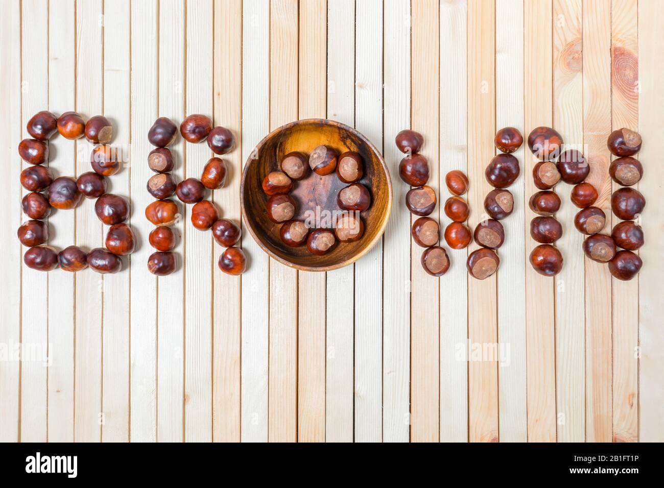 Word brown is laid out with ripe large chestnuts close up using wooden ...
