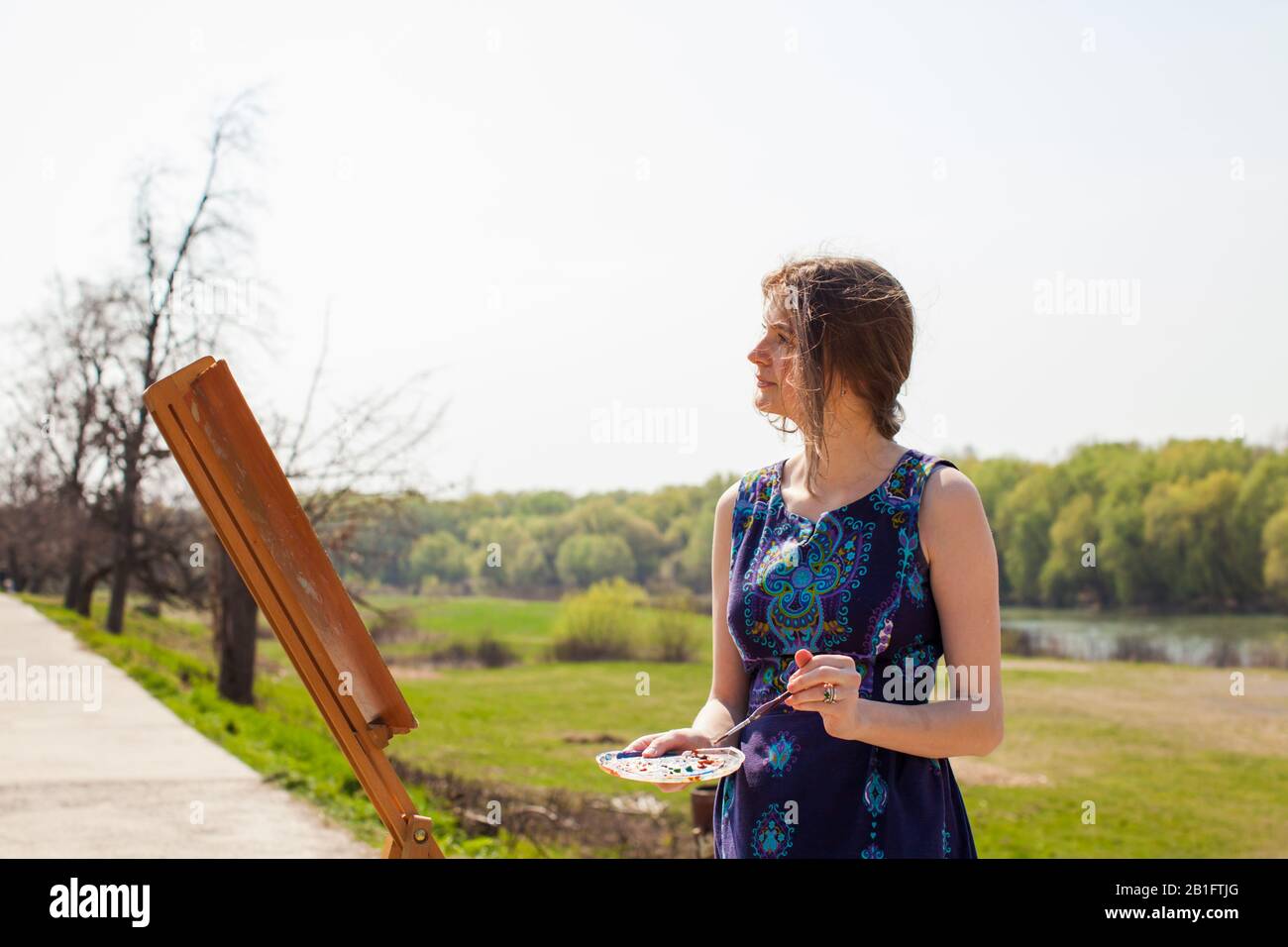Tender creative girl paints a spring landscape outdoors. Art therapy ...