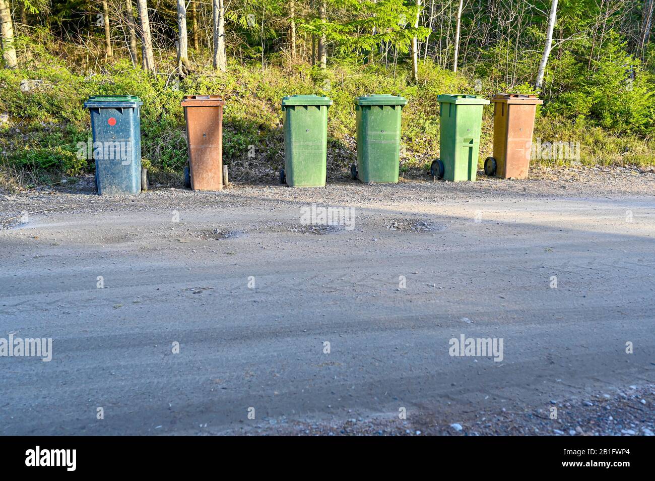 six garbage cans standing near gravel road Stock Photo - Alamy