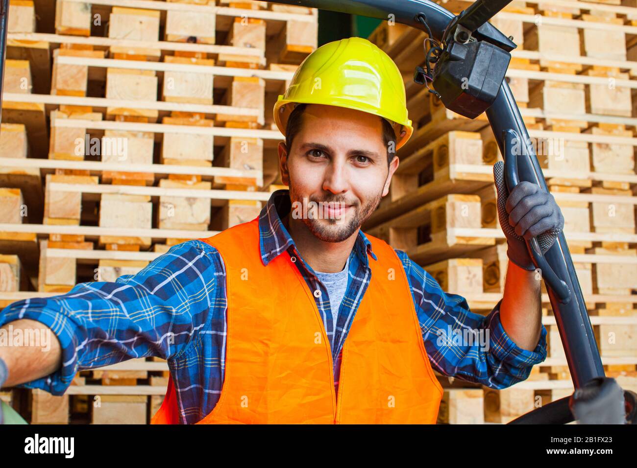 Workman wears protective helmet, vest and gloves. Worker standing near ...