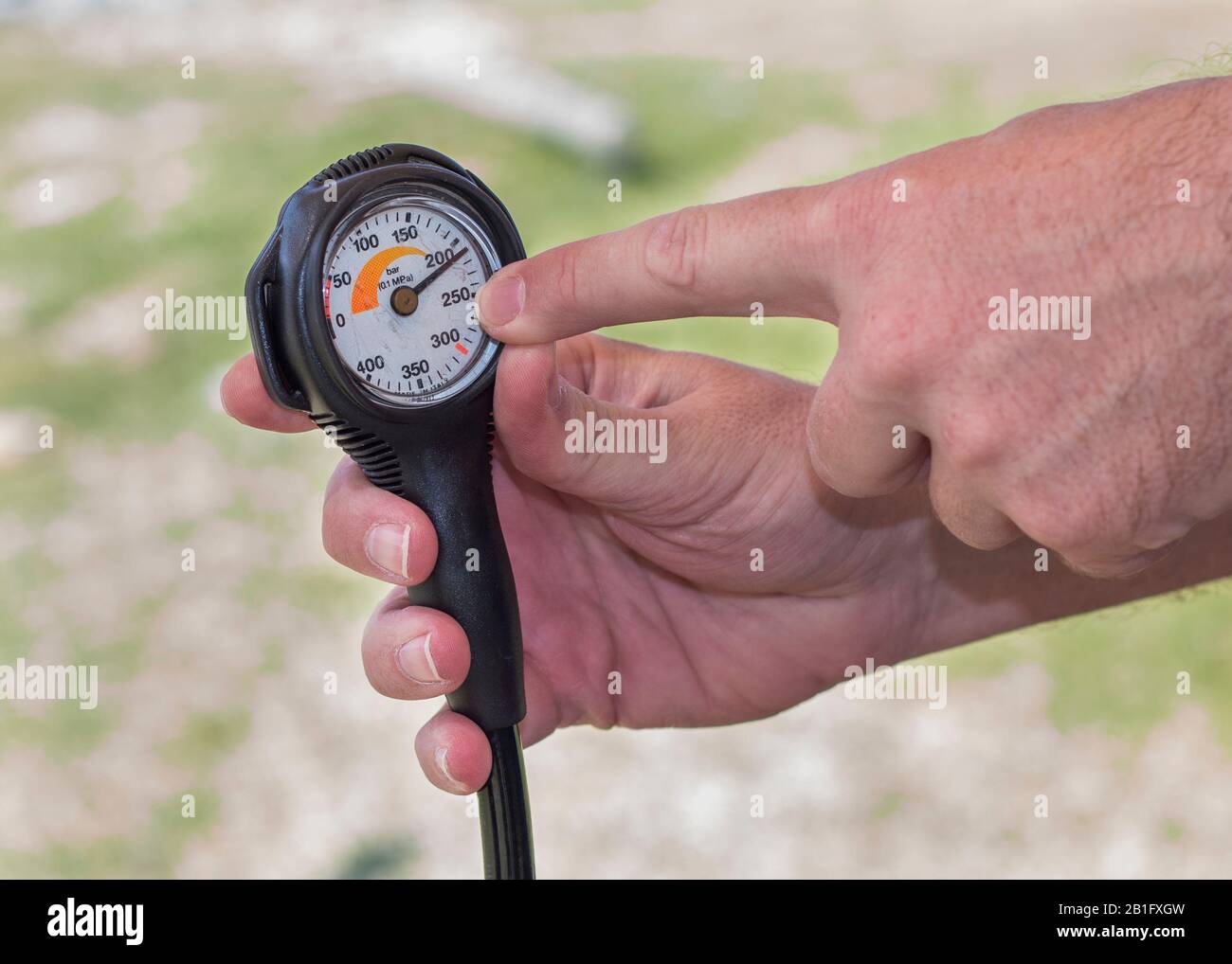Hand holding a scuba diving equipment pressure gauge with finger ...