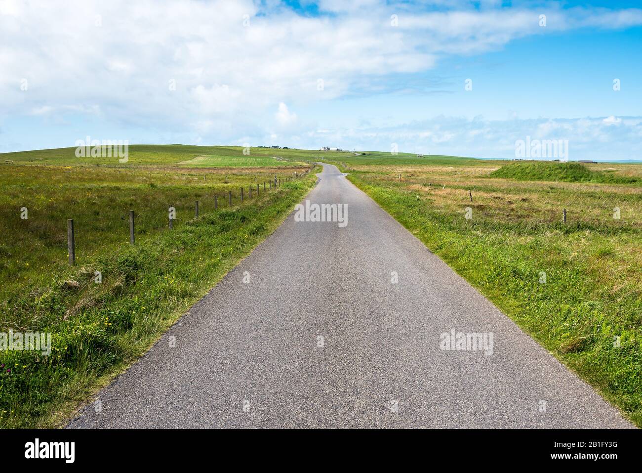 Deserted country road through meadows under blue sky with clouds Stock ...
