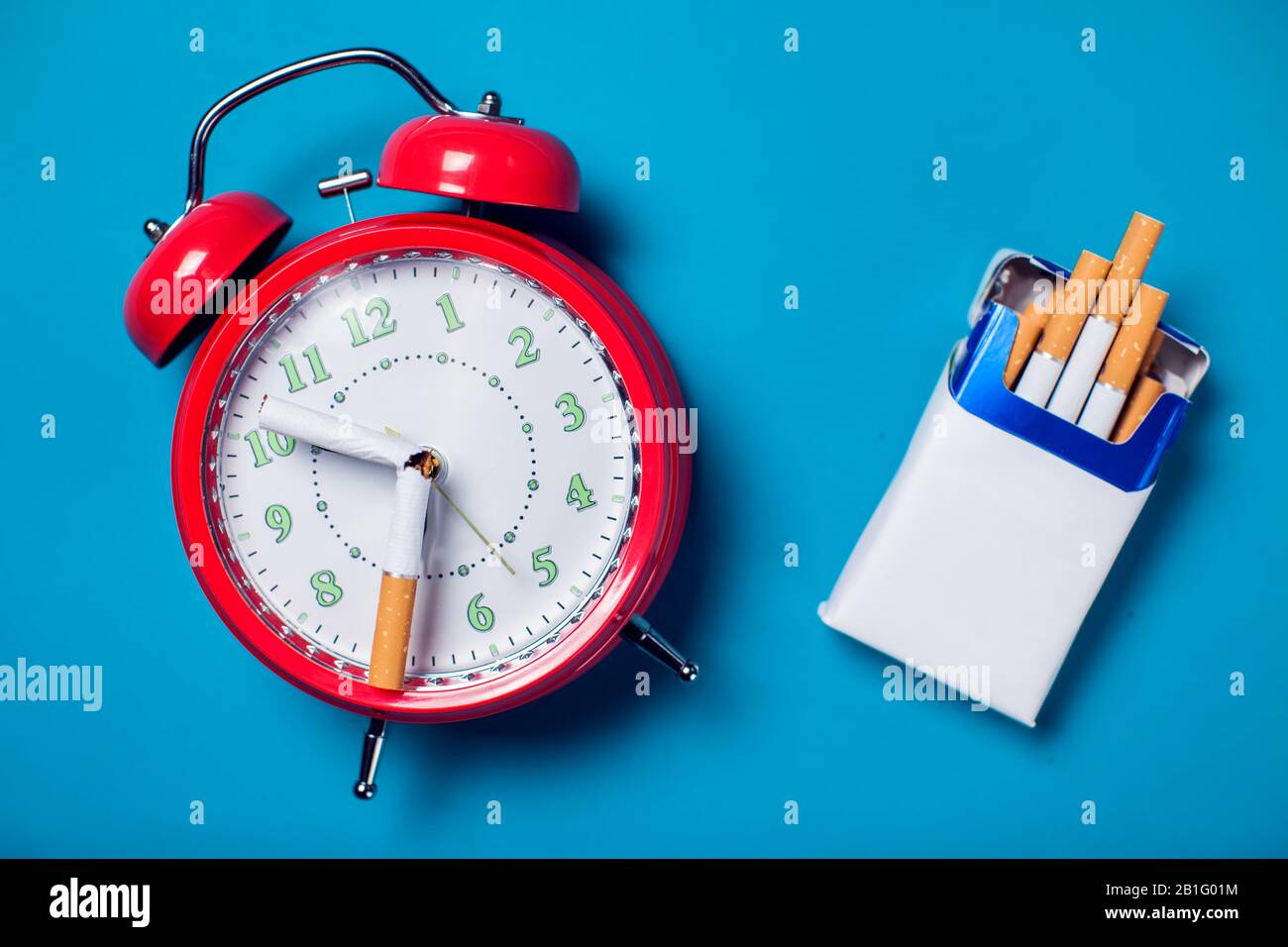 Red alarm clock with broken cigarette instead of clock hands on color ...
