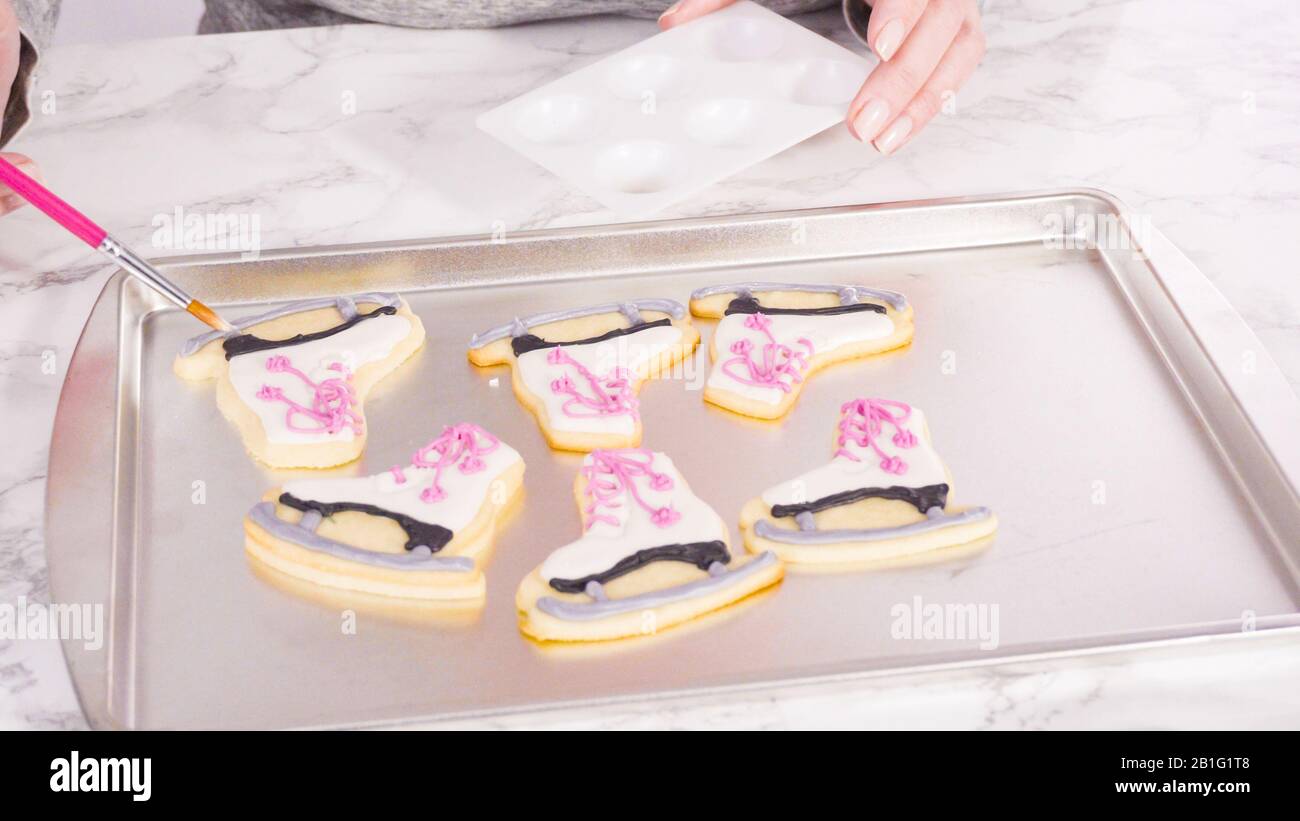 Brushing edible glitter on iced figure skate sugar cookies Stock Photo ...