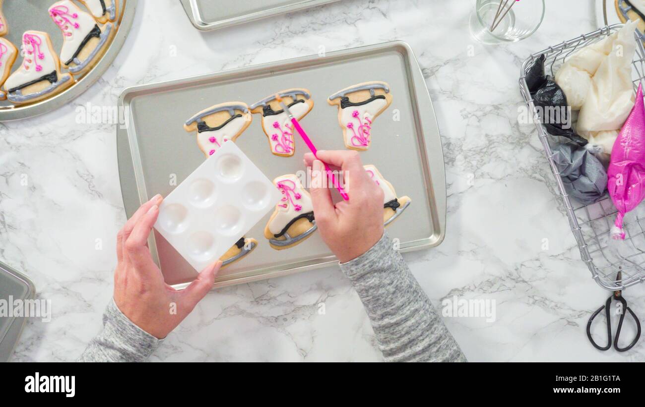 Flat lay. Brushing edible glitter on iced figure skate sugar cookies ...