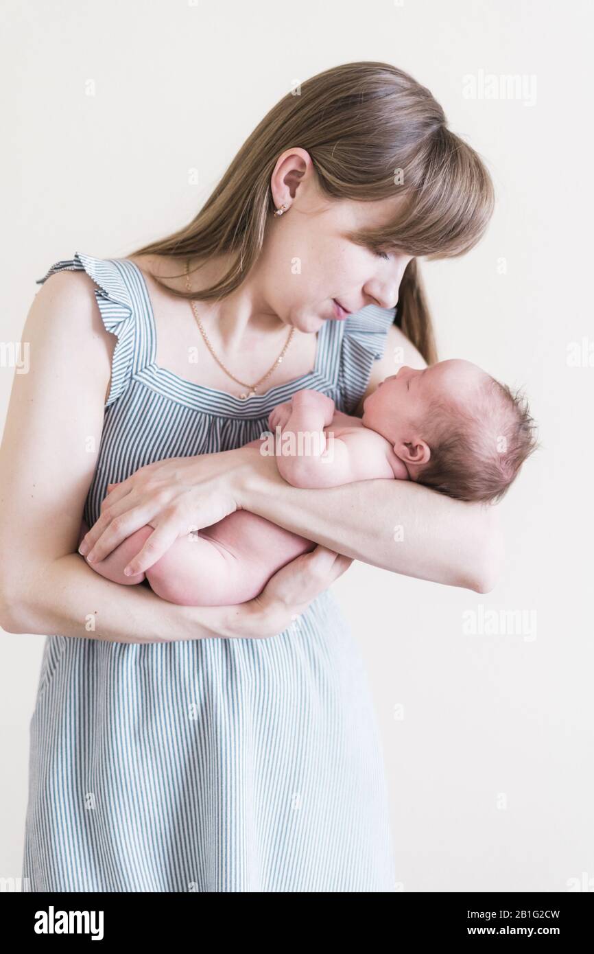 Lifestyle portrait of a young mother and her newborn, three weeks old ...