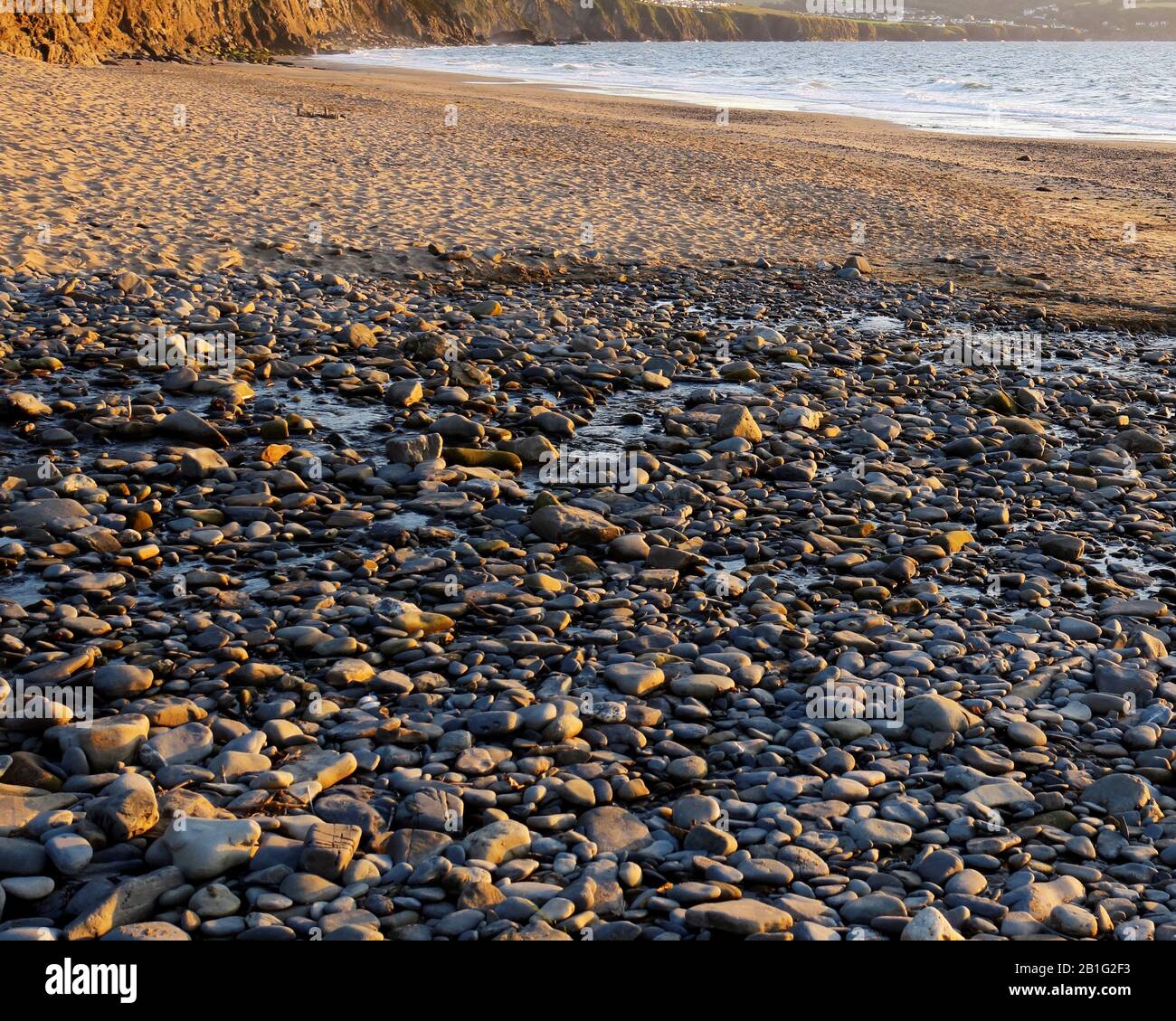 Colour photograph of coastal stones on beach smoothed and rounded by ...