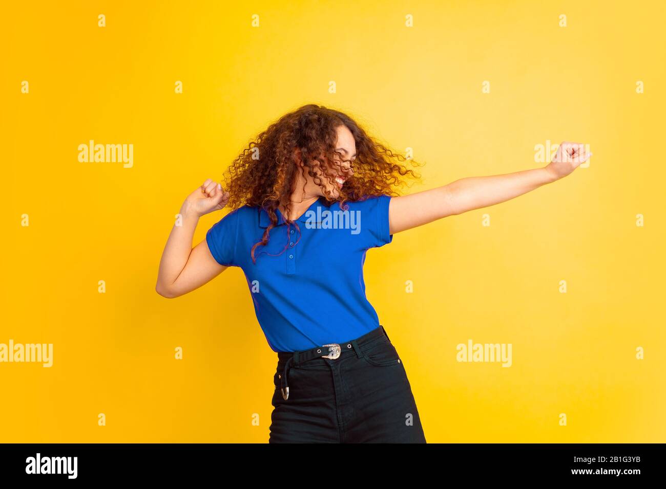 Dancing with flying hair. Caucasian teen's girl portrait on yellow ...
