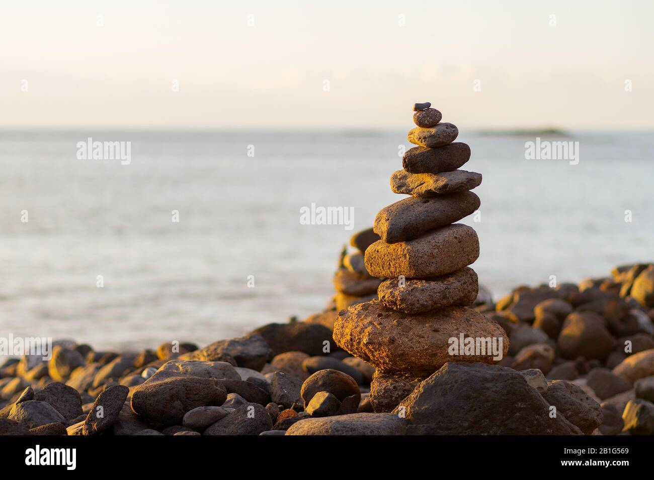 Balanced stone pyramide on shore of the ocean at dawn. Sea pebbles ...