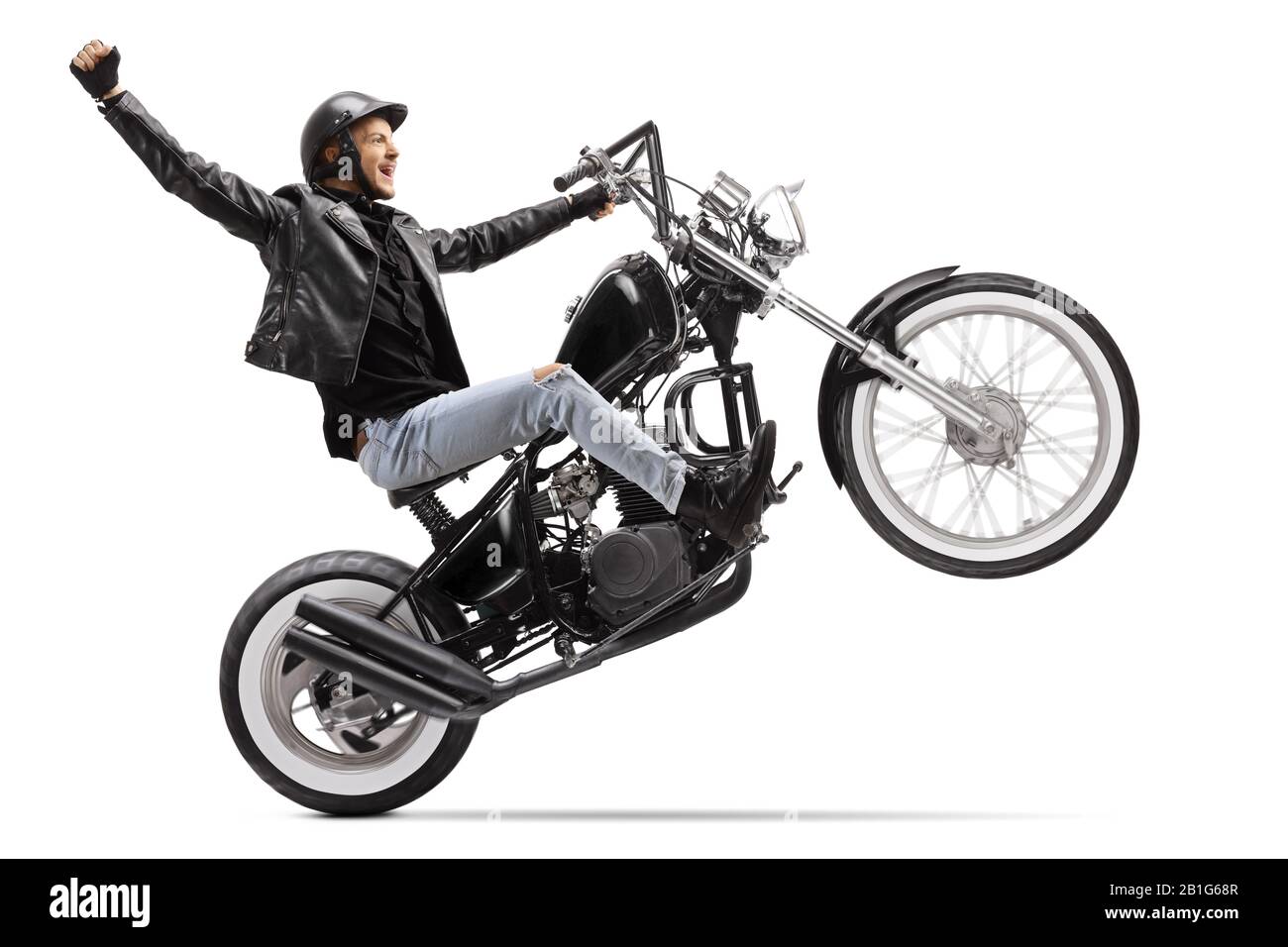 Happy young male biker riding a custom motorbike with one wheel up and ...