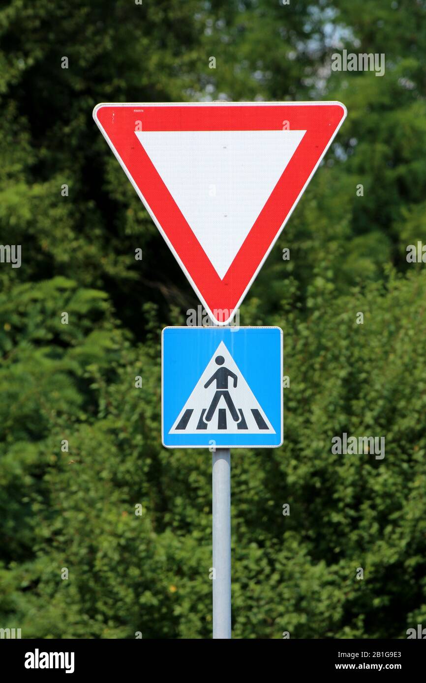 Red and white triangle give way or yield road sign above pedestrians ...