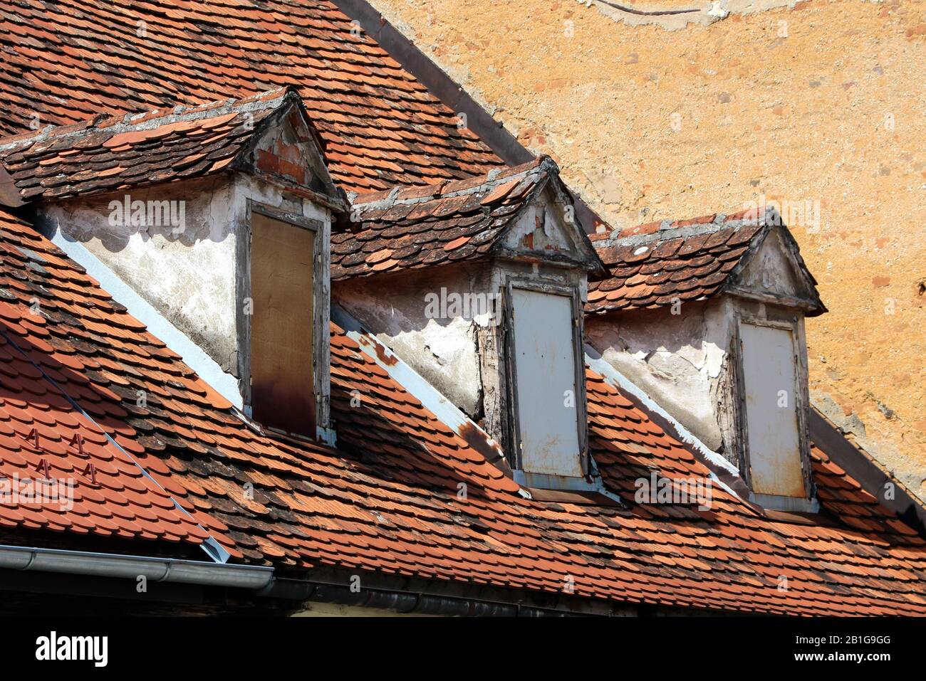 Row of old style roof windows closed with wooden boards covered with ...