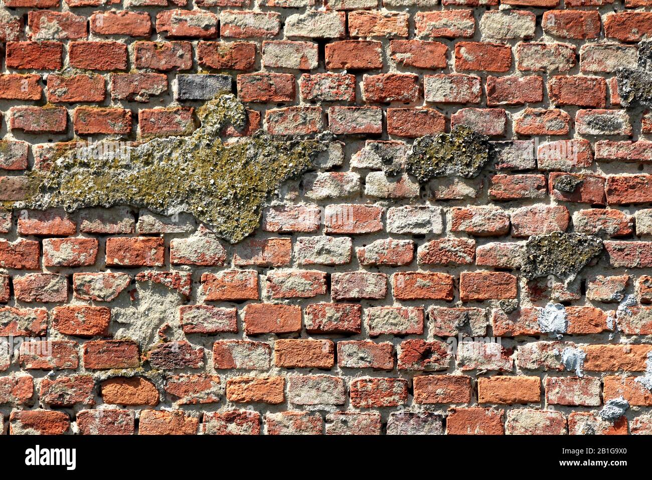 Texture of old faded red brick wall with concrete patches covered with ...