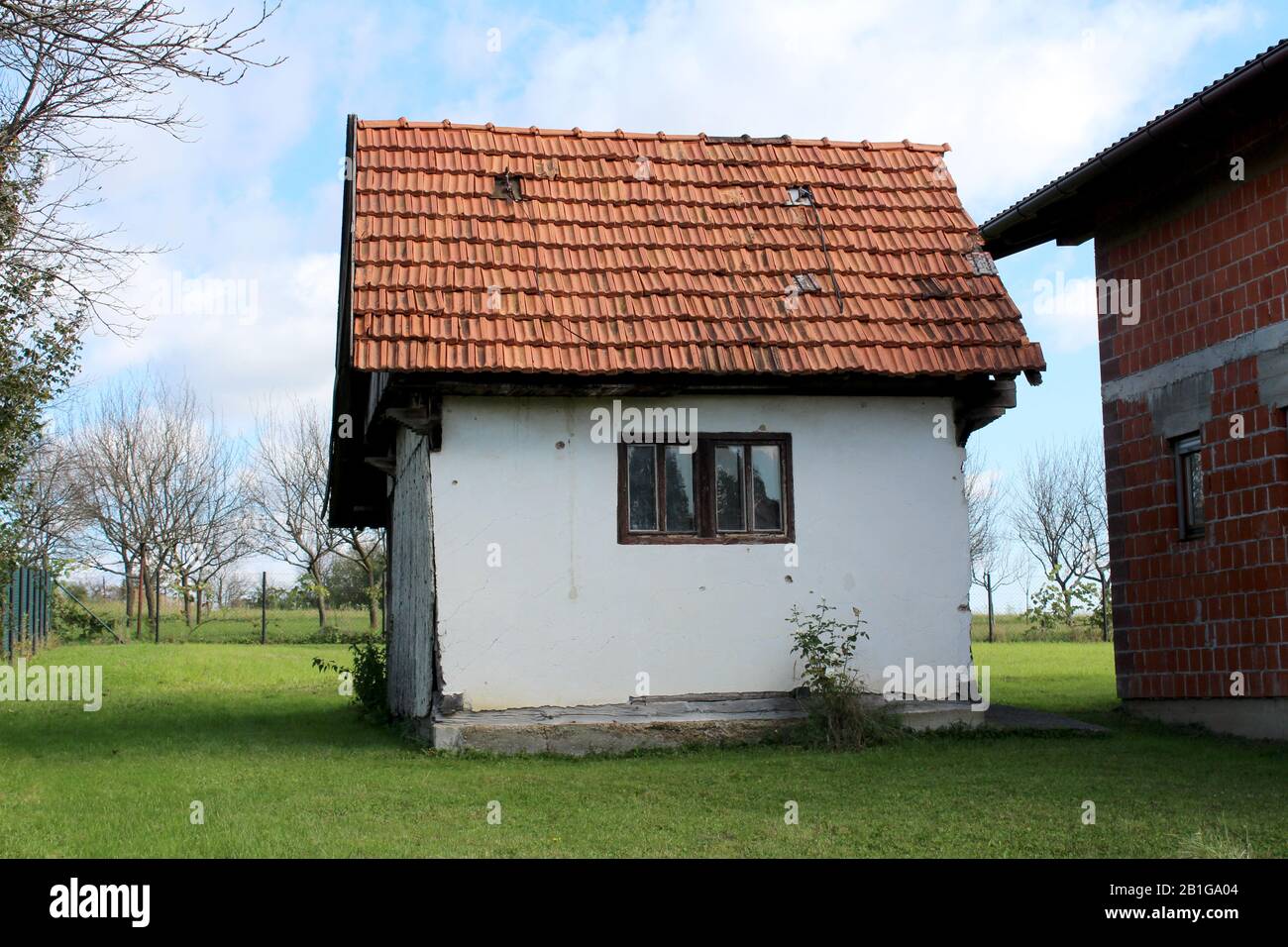 Tiny abandoned old family house ruins with cracked white facade and ...
