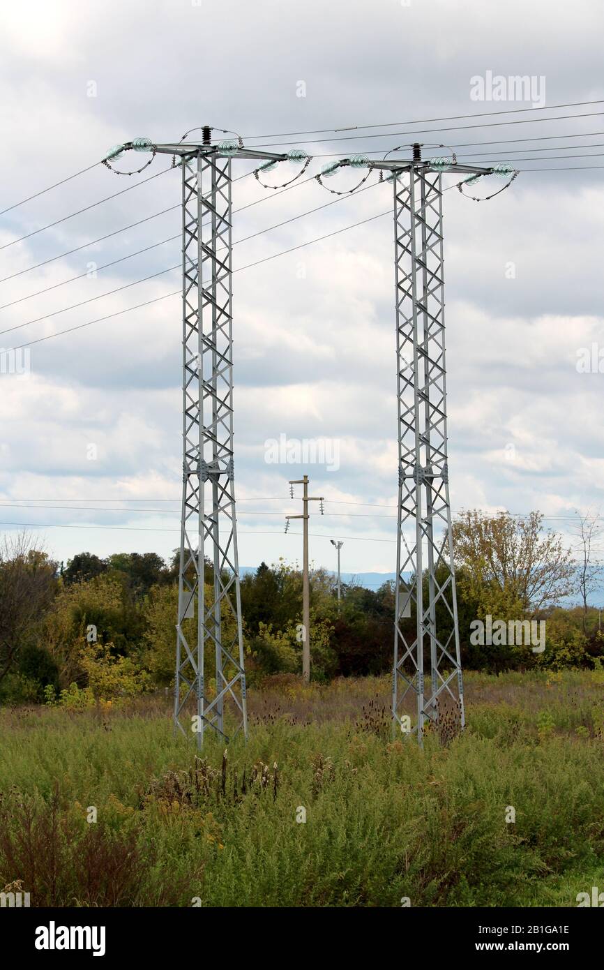Two tall narrow metal power line utility poles with multiple electrical ...