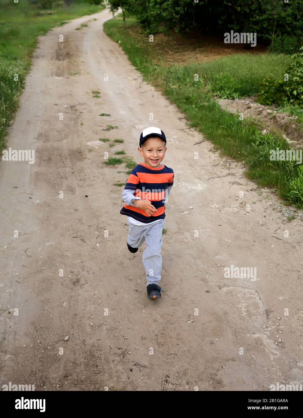Happy little boy running on the country road Stock Photo - Alamy