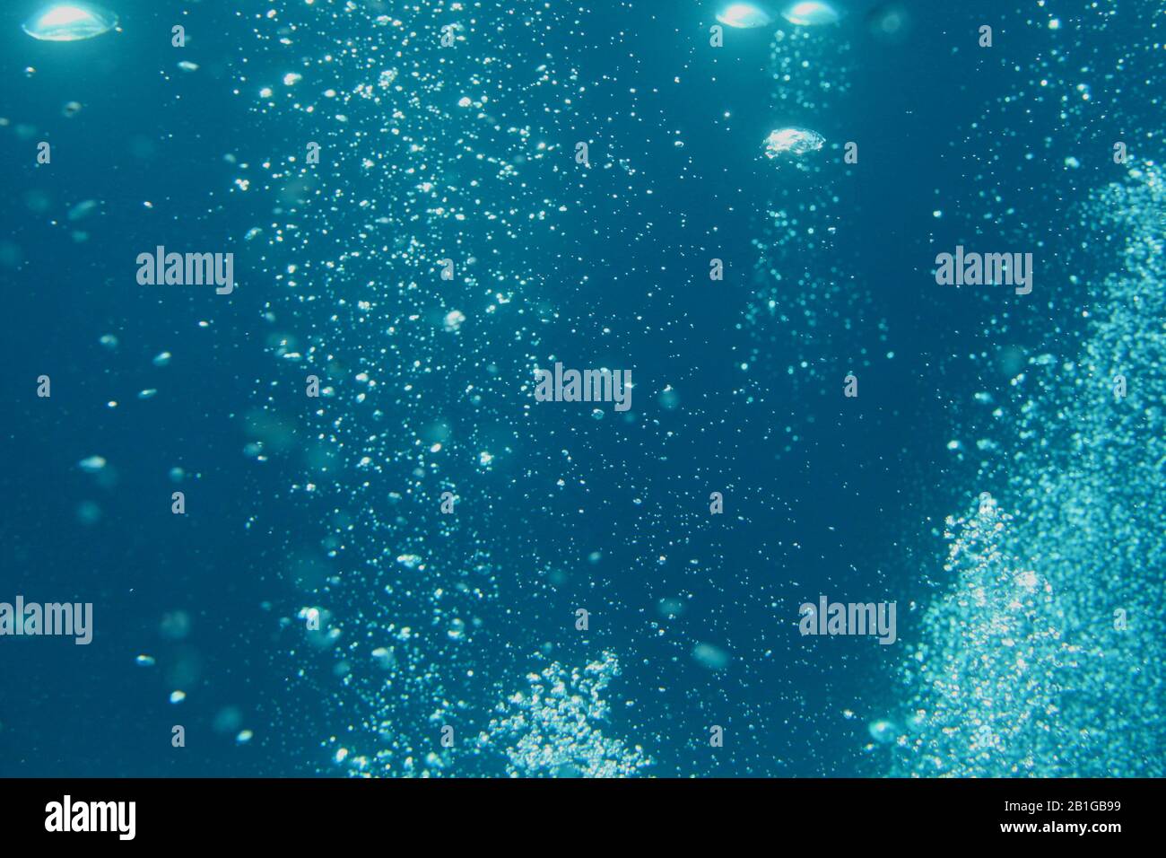 Blue ocean waves from underwater with bubbles. Light rays shining ...