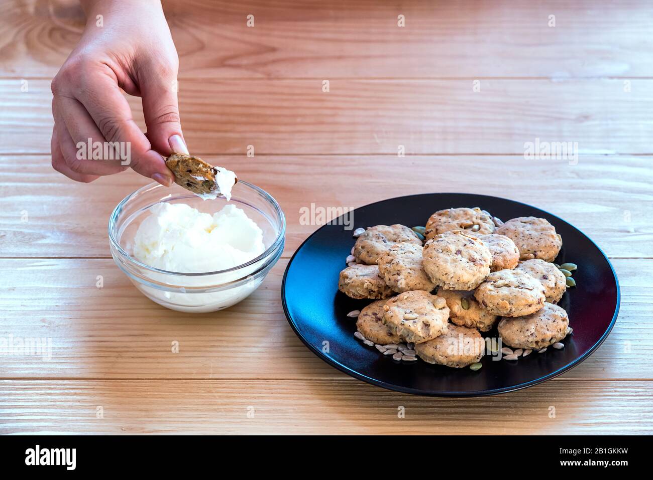 Female Hand dipping Salted crispy integral cracker with sunflower and ...