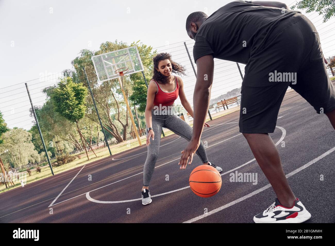 Outdoors Activity. African couple guy dribbling back view close-up ...