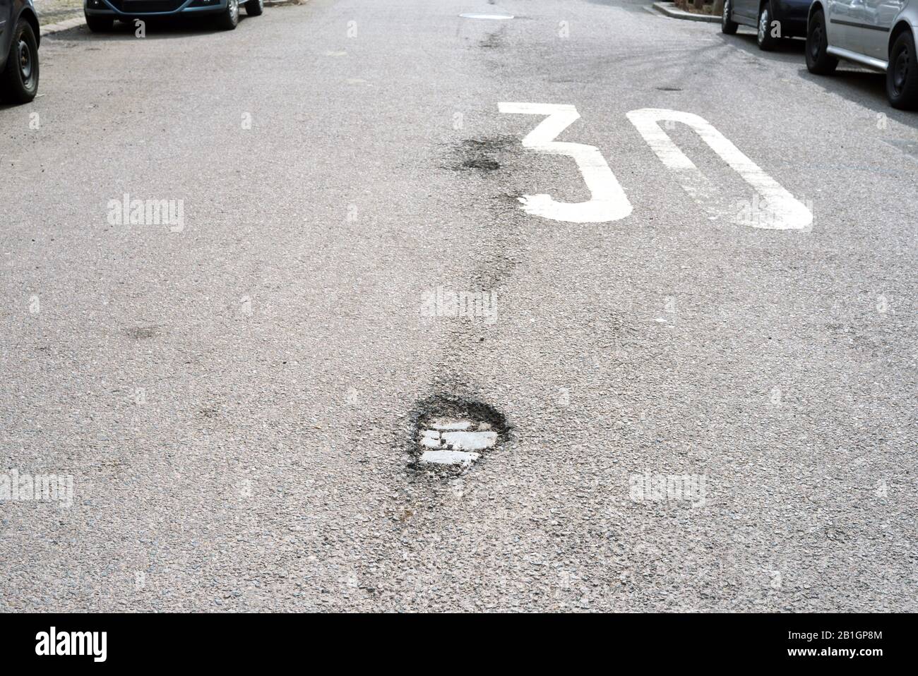 Broken street with cars, a hole on the surface and a speed limit on the ...