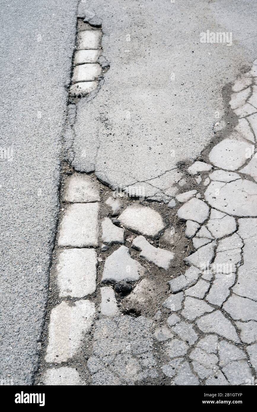 Broken road with holes and different surfaces vertical Stock Photo - Alamy
