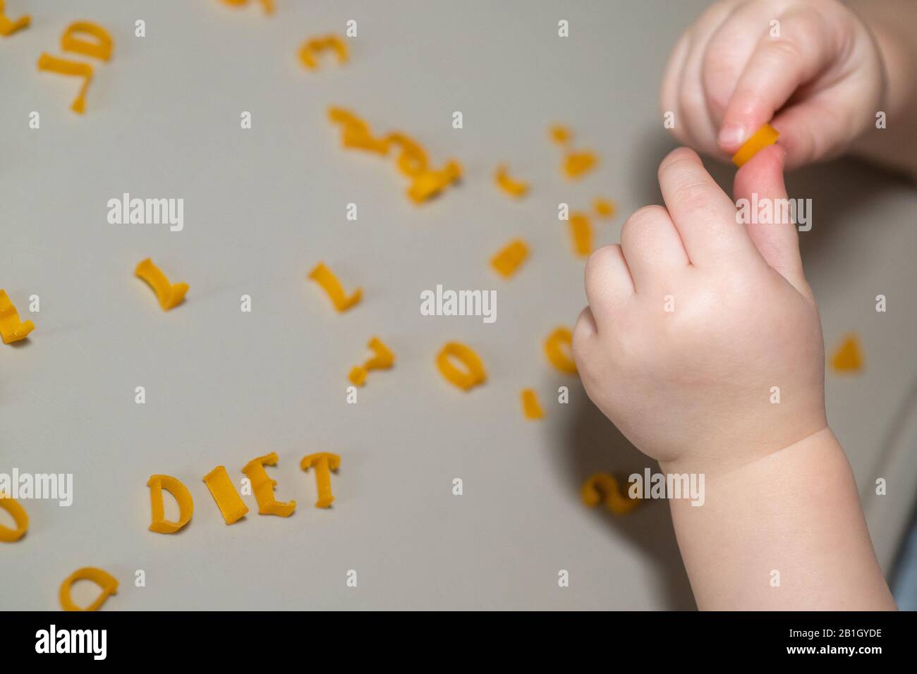 hand of child collecting letters from pasta from table. development of ...