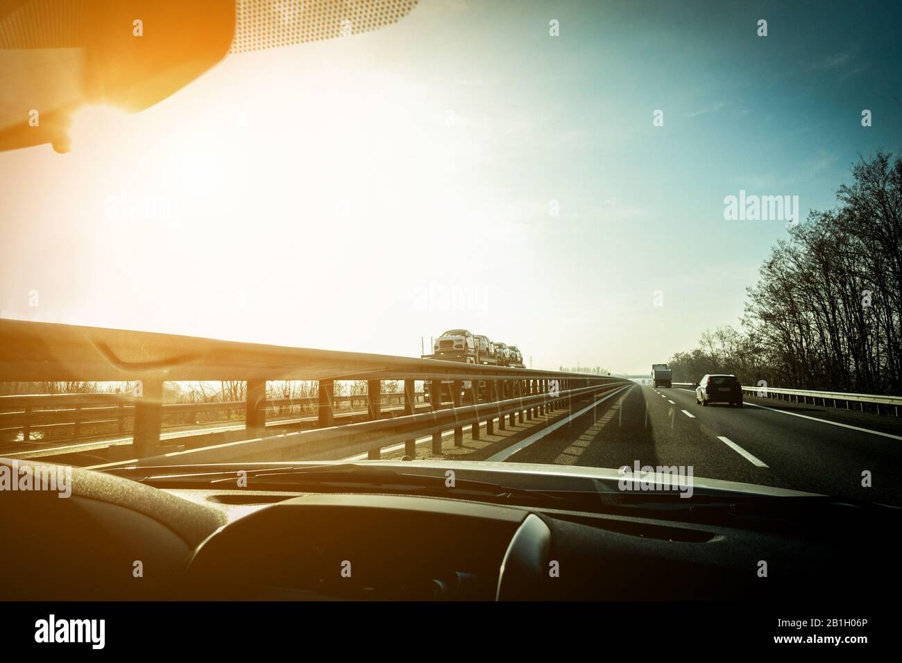 Car window view of trucks speeding in motorway with back sun light ...