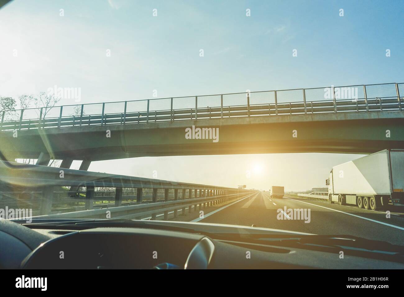 Car window view of trucks speeding in motorway under a overpass bridge ...