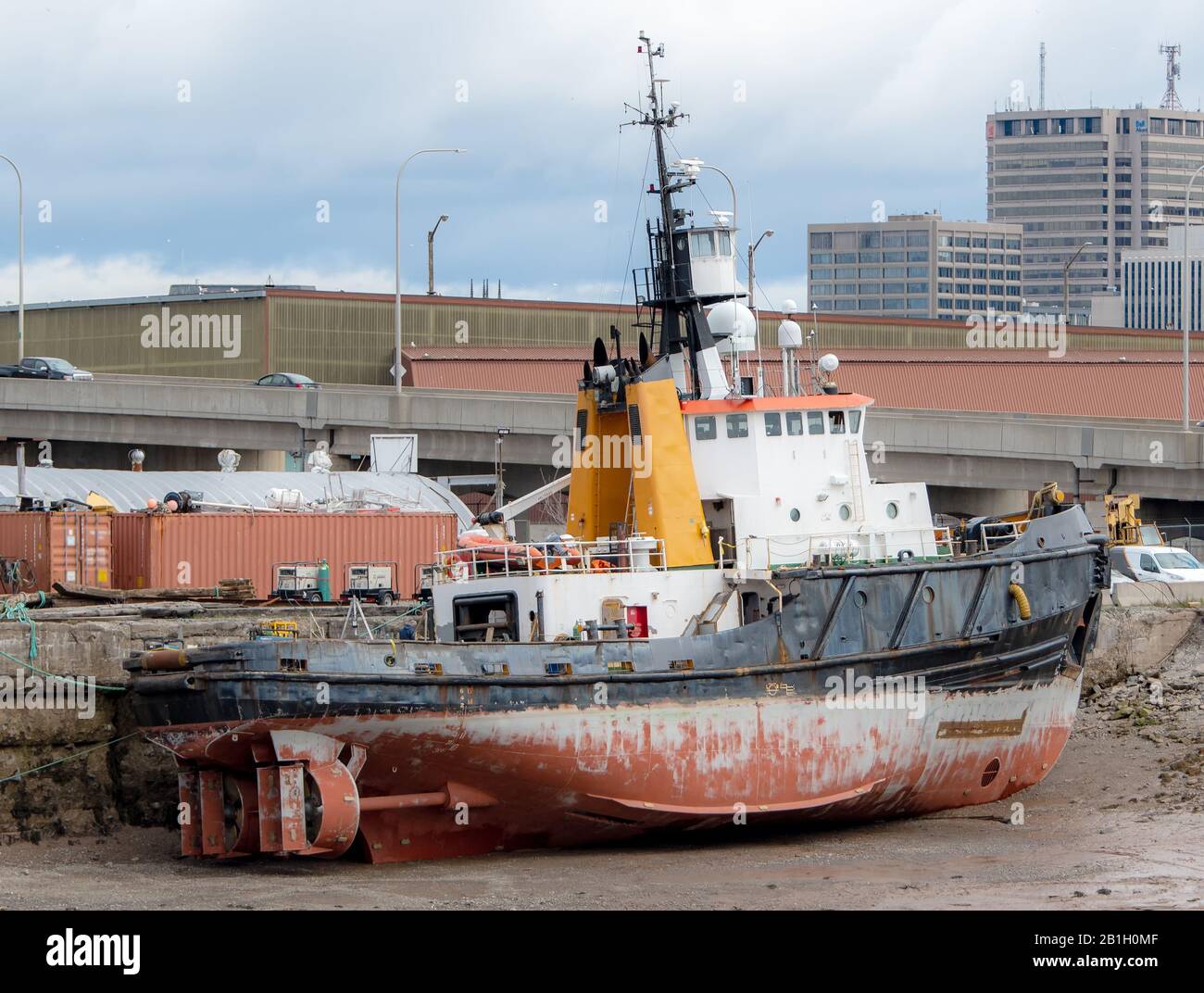 An old, unidentified tugboat resting on the beach at low tide. It is ...