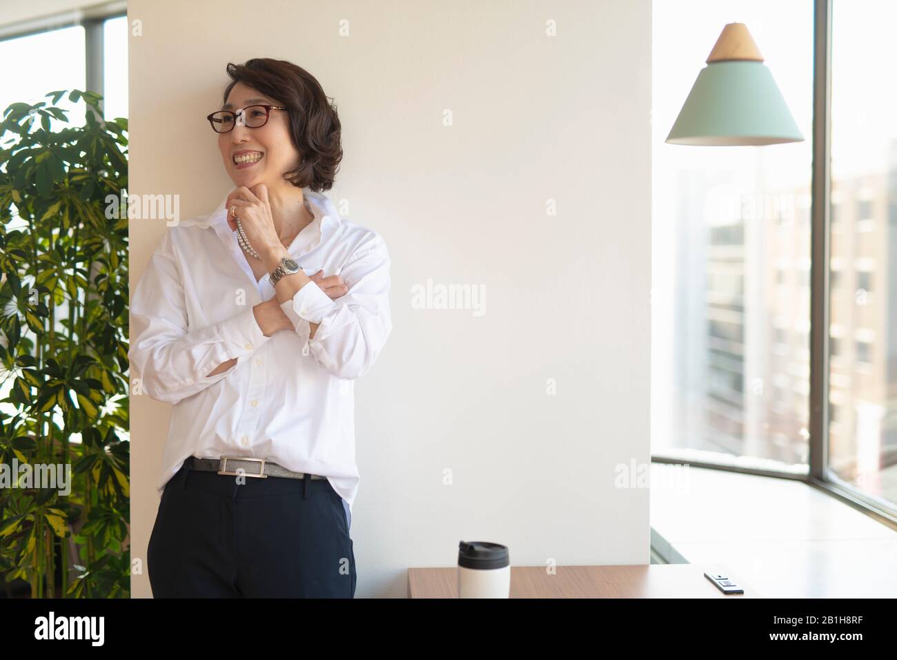 Smiling woman standing at window Stock Photo - Alamy