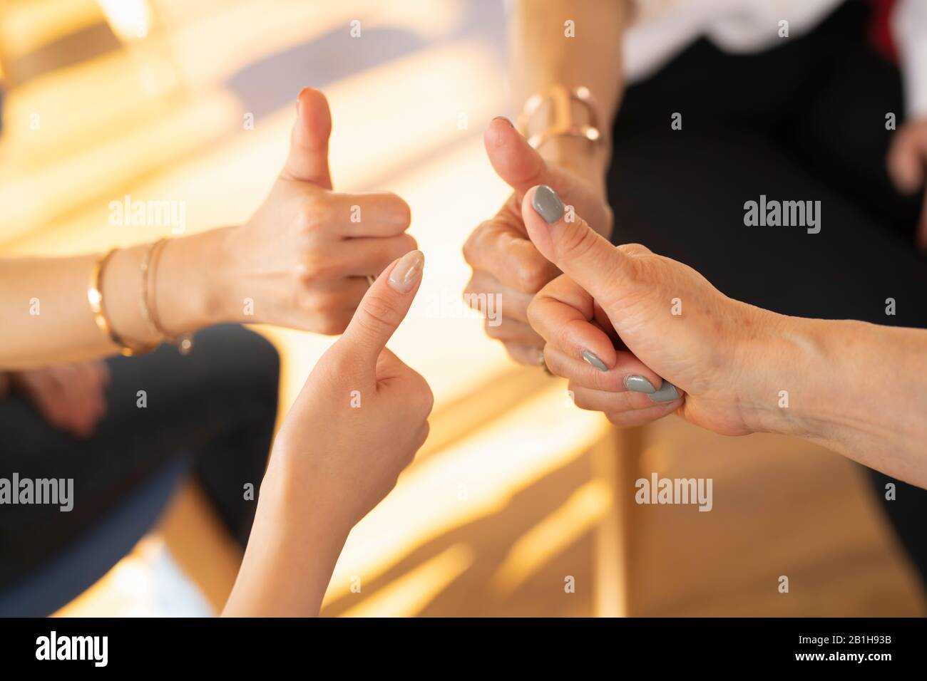 Four women's hands showing thumbs up sign Stock Photo - Alamy