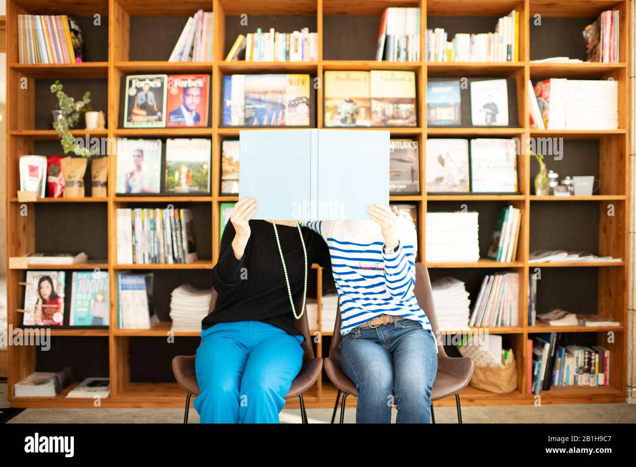 Two women reading book Stock Photo - Alamy