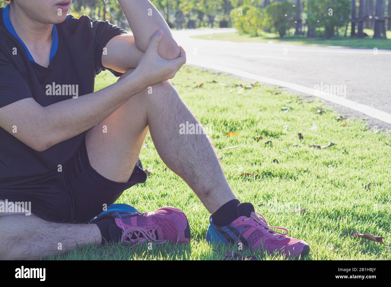 A male athlete suffering from arm and elbow pain and injury at the park ...