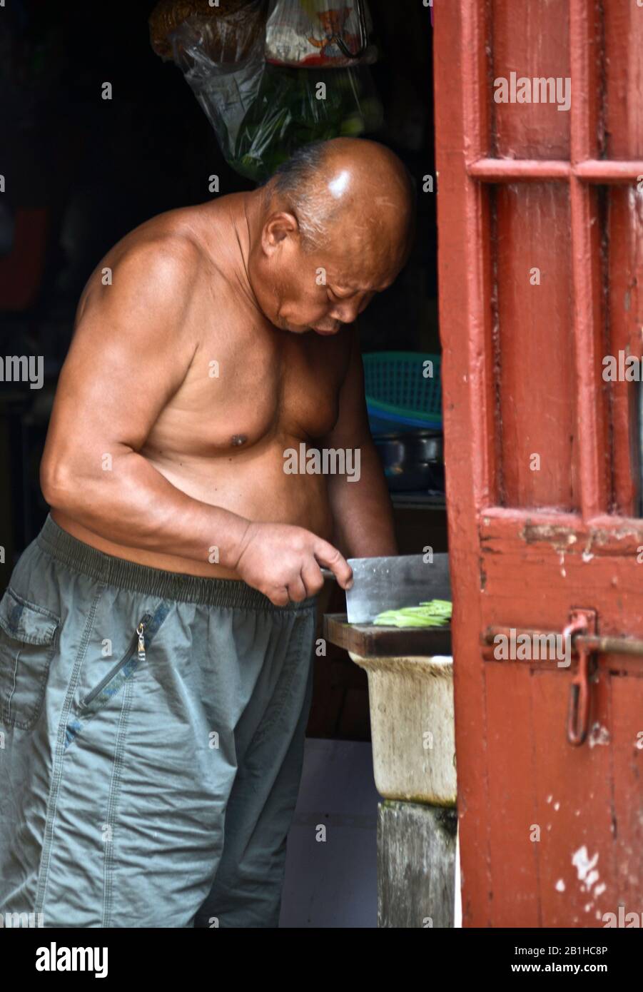 A shirtless chef of a street food store in Shanghai Old Town, Penglai ...