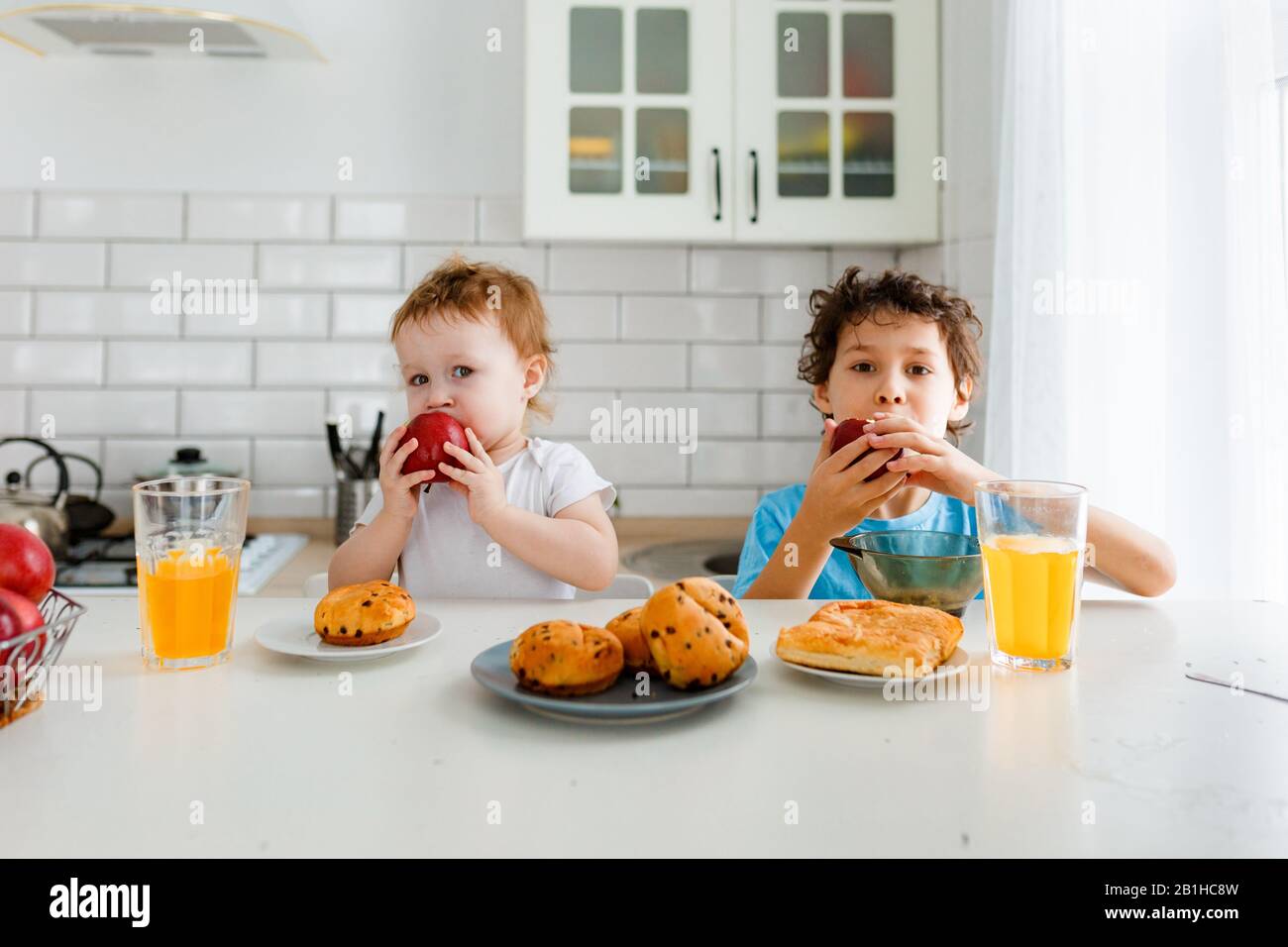 Happy children real brother and sister having breakfast with fruits in ...