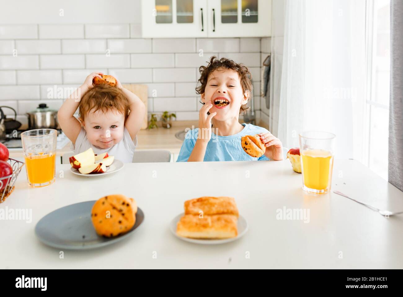 Happy children real brother and sister having breakfast with fruits in ...
