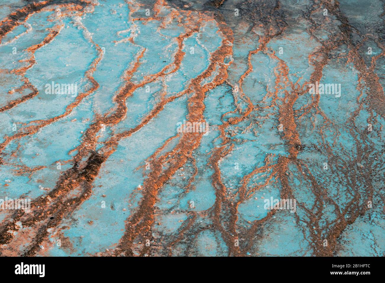 Aqua blue wet ground with crusty brown patterns and lines in background ...