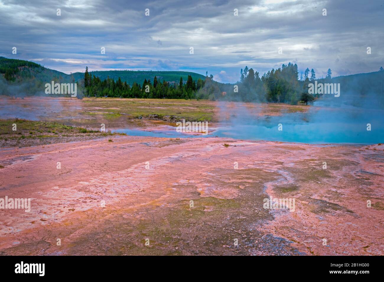 Colorful ground surrounding blur hot spring with steam rising up off ...