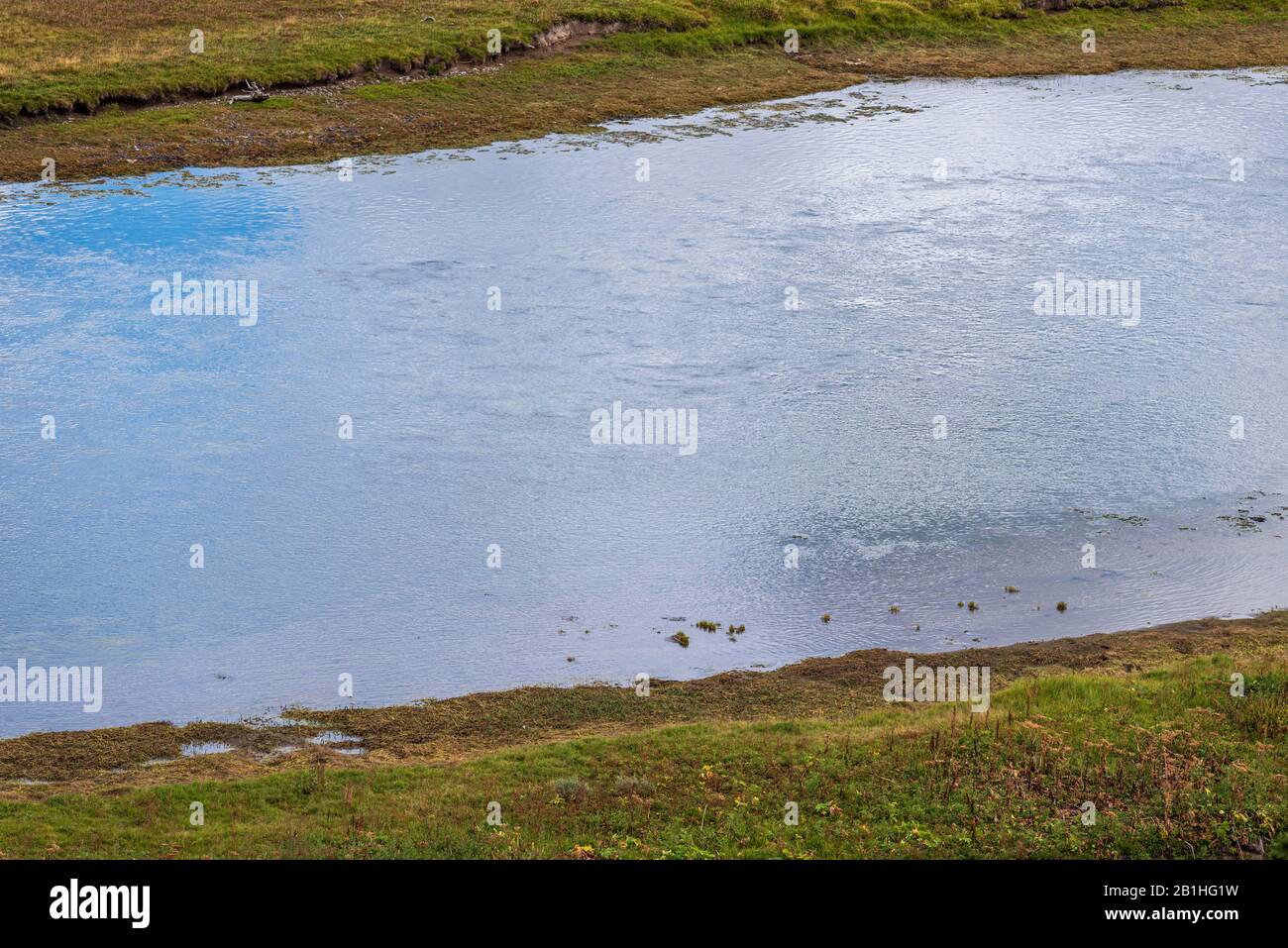 Stream reflecting blue sky, green grassy stream banks Stock Photo - Alamy