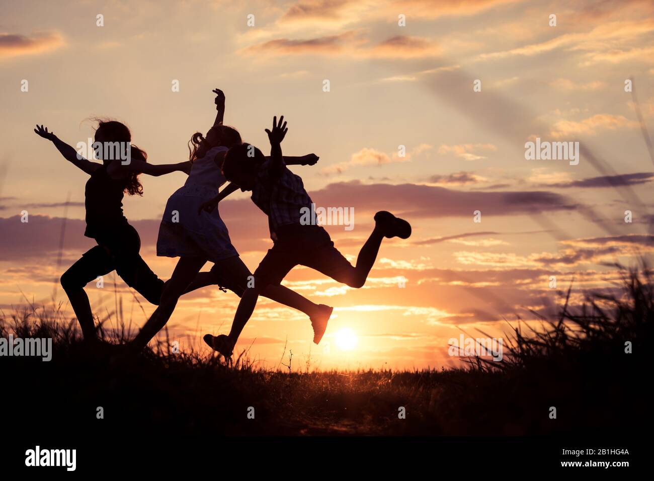 Happy children playing in the park at the sunset time. People having ...