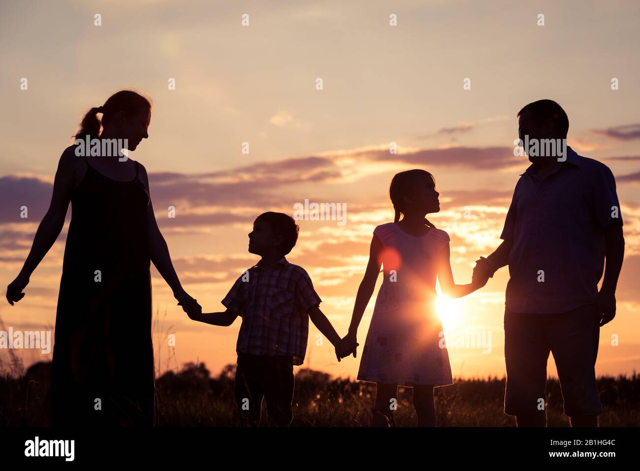 Happy family standing in the park at the sunset time. People having fun ...