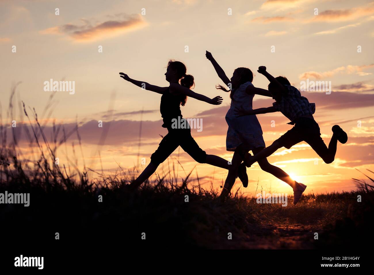 Happy children playing in the park at the sunset time. People having ...