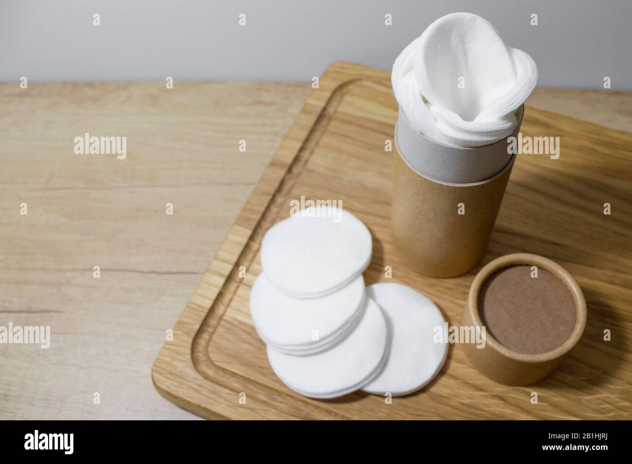 Paper tube with white cotton disks inside on wooden board. Recycle ...