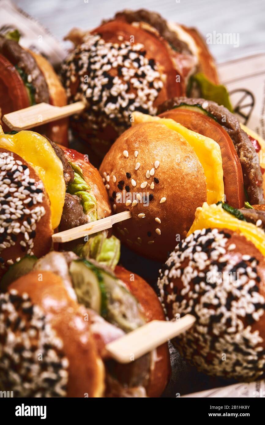 A large set of many hamburgers, cheeseburgers laid out on the table ...