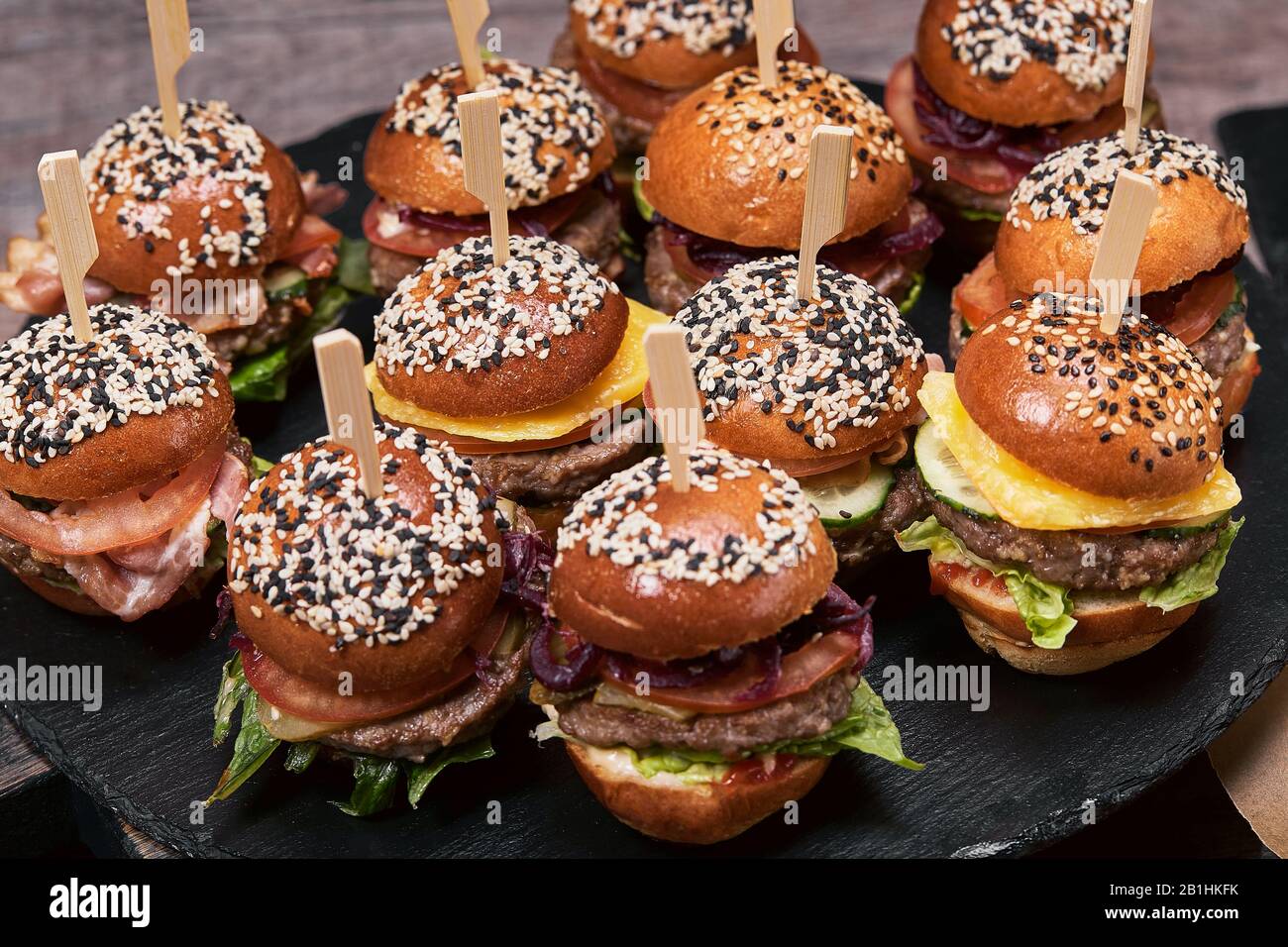 A large set of many hamburgers, cheeseburgers laid out on the table ...