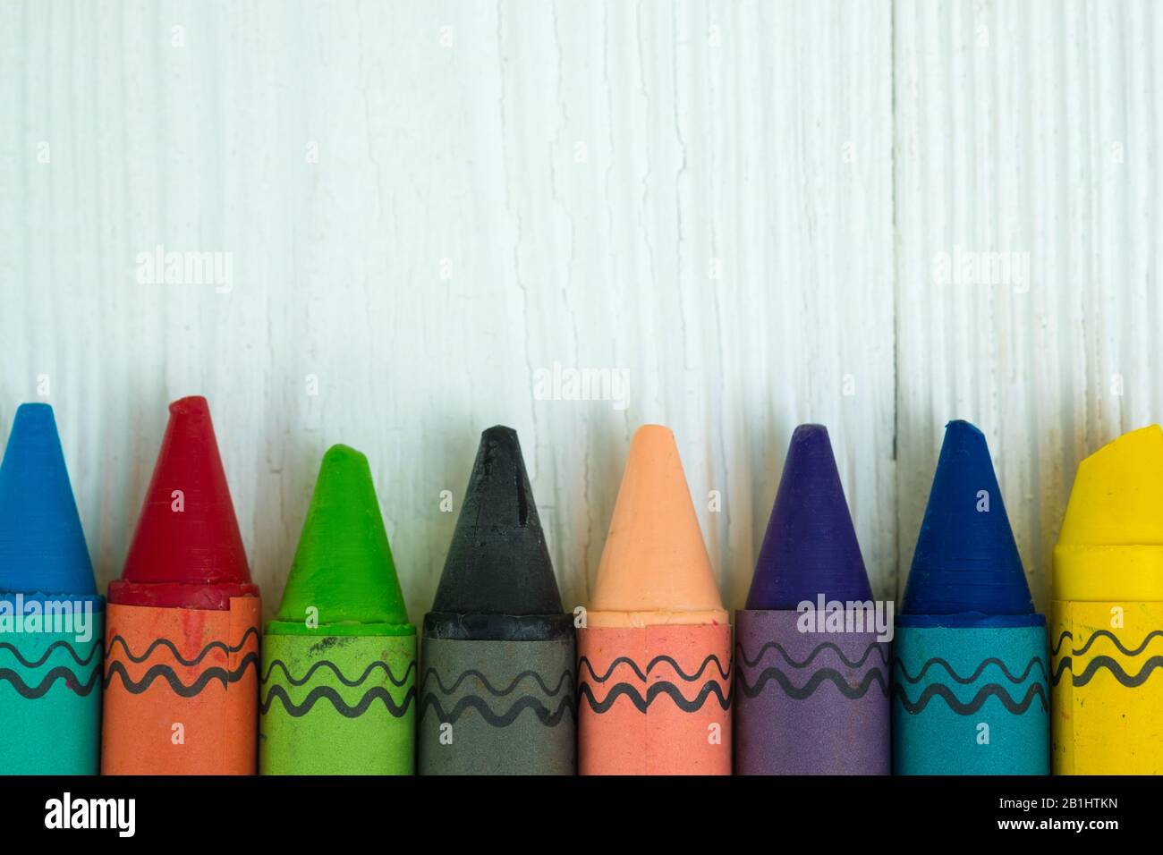 Colourful wax crayons pencils on white wood table with copy space for ...